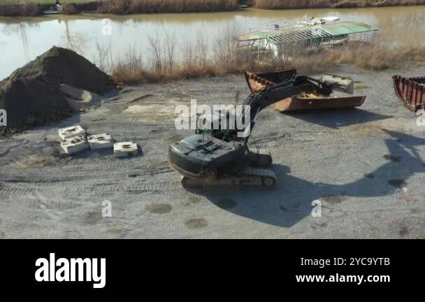 Above view, excavator pulls over ground part of old freight vessel's ...