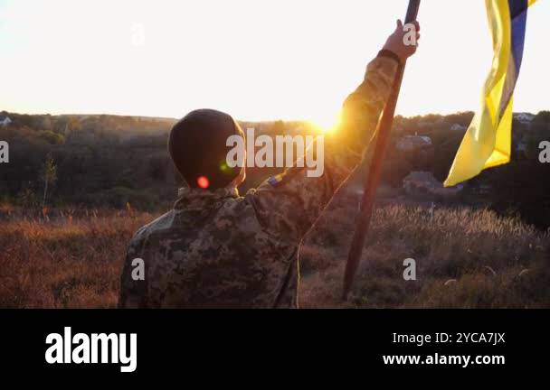 Young soldier of ukrainian army raised blue-yellow banner on liberated ...