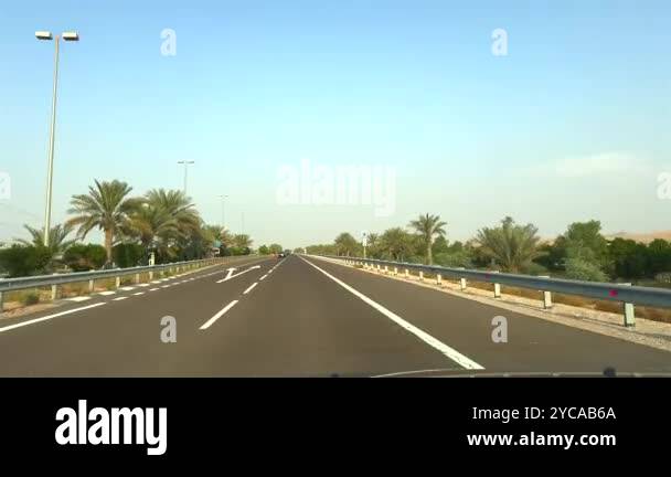 Desert highway stretches into distance with brown road and lush green ...