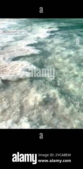 Salt formations meet turquoise water, sunlight brightens rough textures ...