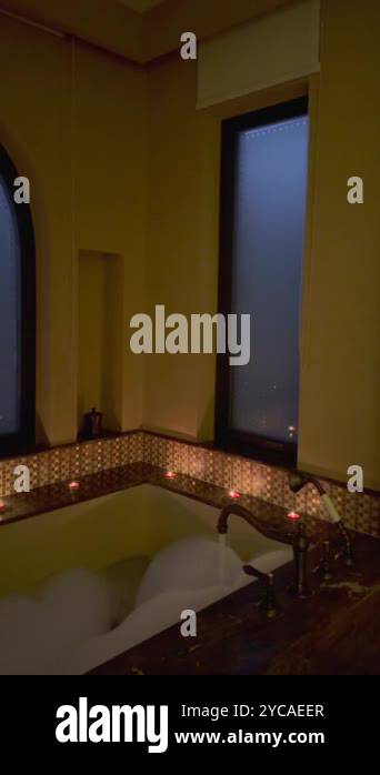 Oriental-themed bathroom with luxurious bubble-filled bathtub, running ...