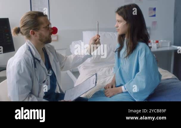 Side shot of cheerful male pediatric neurologist with red nose checking ...