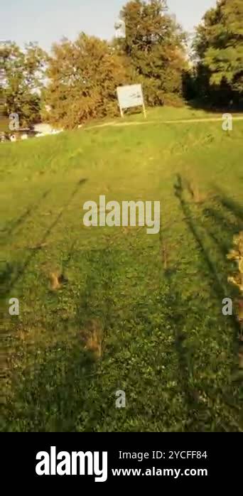 This FPV drone footage shows a park with trees, a walking path, and ...