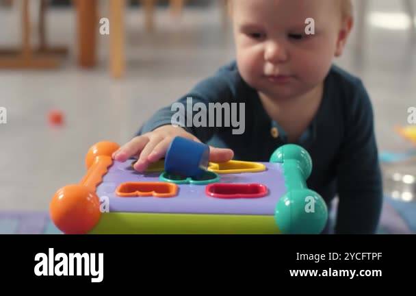 Cheerful toddler plays with a colorful shape sorting toy designed to ...
