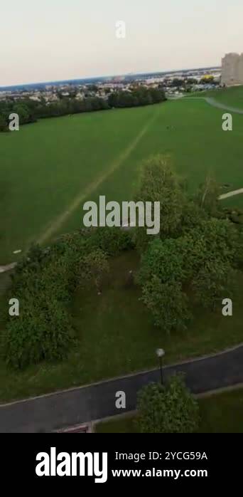 This FPV drone footage shows a park with trees, fields, and a ...