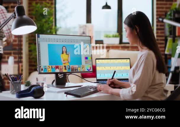 Asian graphic designer uses editing software for photo retouching in a ...