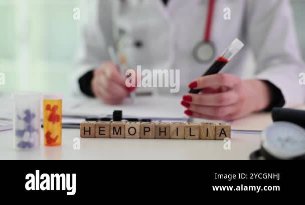 Doctor holds test tube with blood with word hemophilia on cubes closeup ...