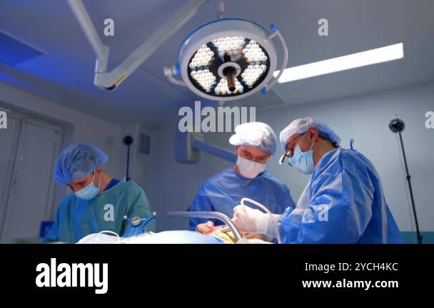 Two male doctors and nurse stand under the round lamp near operating ...