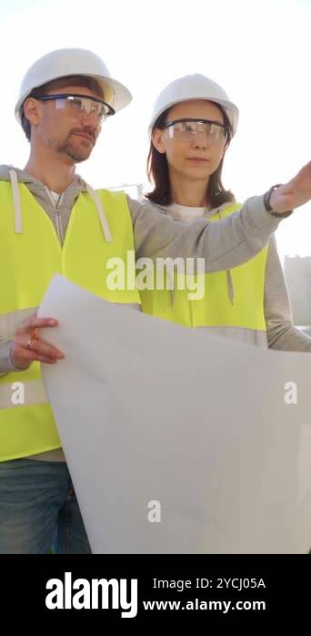 Man and woman architects or engineers wearing safety hard hats and ...