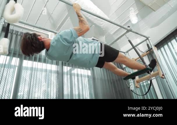 Man gripping bar on pilates trapeze table for core strength and upper ...
