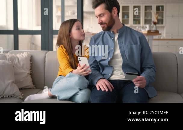 Joyful family little Caucasian girl daughter choose goods online shop with mobile phone dad man ...