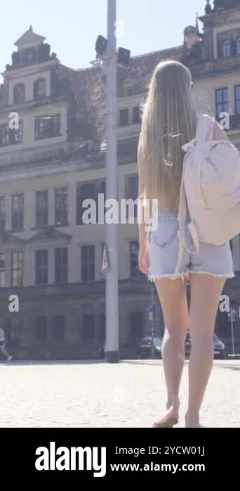 A woman strolls barefoot on a charming cobblestone street, admiring ...