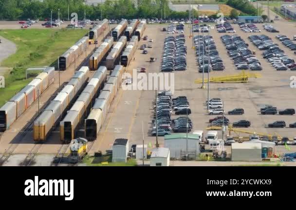 Loading of new cars on long haul train auto racks at automotive plant ...
