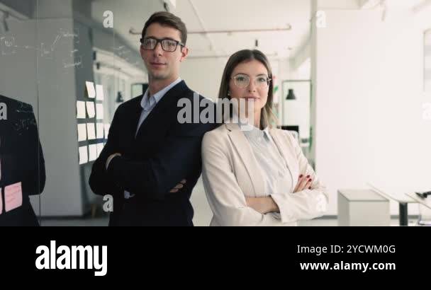 Businessman and businesswoman standing confidently in office, wearing ...