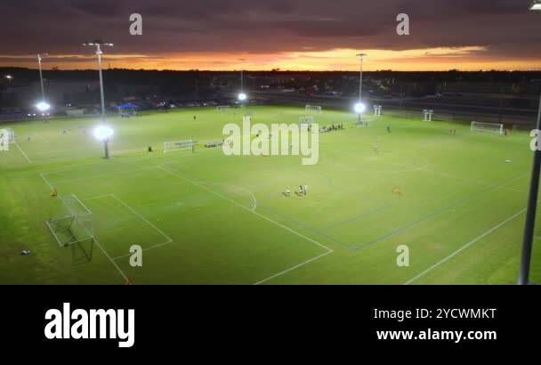 Public sports stadium with school kids playing football game in evening ...