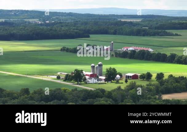 Rural agricultural farm barn and silos between green farmlands in ...
