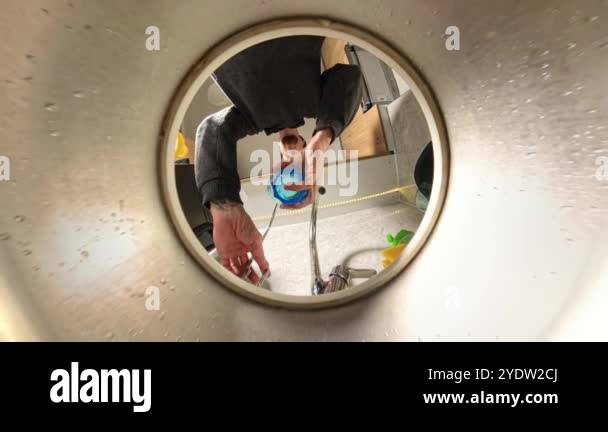 Macro view from inside a Metallic Sink, showing a Man pouring and ...