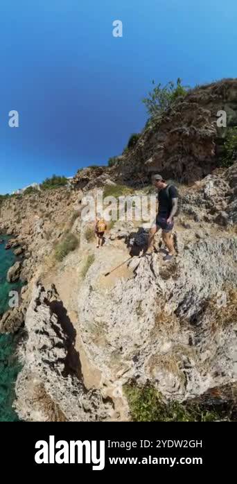 Vertical video. 360 degree camera A Man and Woman hike along a narrow ...