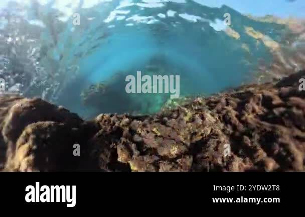 Underwater view as a man stands on the edge of a sea cliff, lowering ...