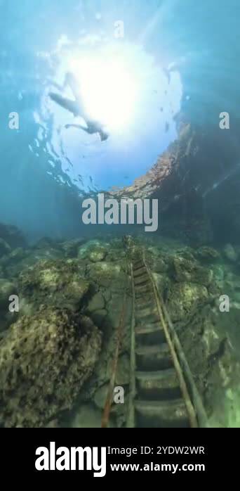 Vertical video. Close-up of an Old Rusty Ladder submerged underwater ...