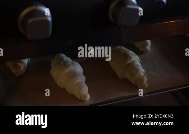 Croissants bake inside the oven, puffing up with a golden finish. A ...