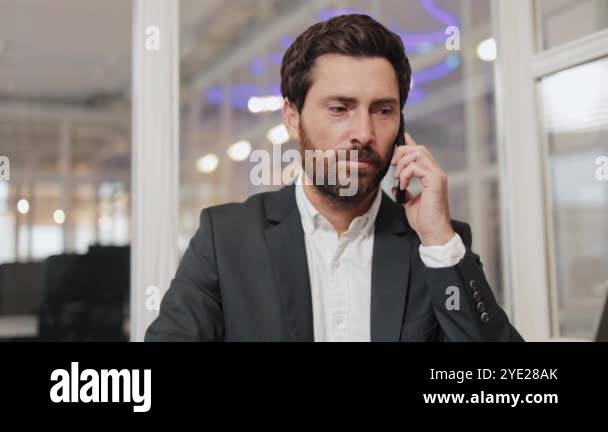 Businessman in a suit is talking on phone. Closeup smiling man talking mobile phone in office ...