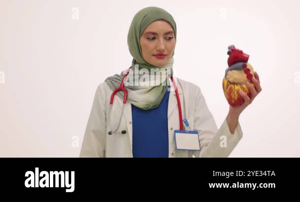 Woman cardiologist in hijab shows heart model on white. Muslim female ...