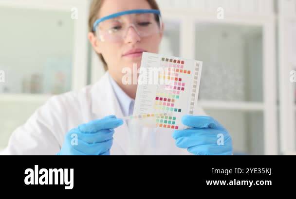 Woman scientist holds pH test strip comparing with color chart after ...