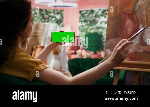 Painter holding a device with isolated mockup screen in art studio ...