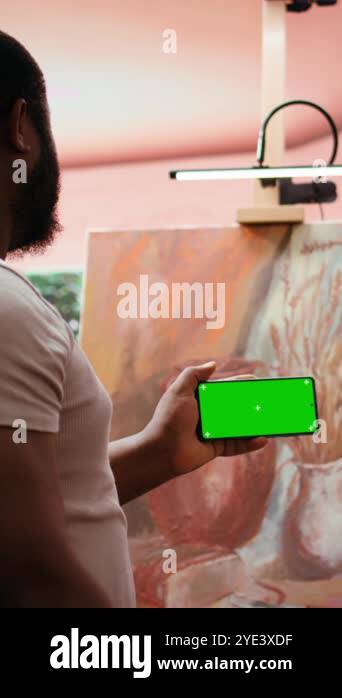 Vertical Video Young artist looking at isolated chroma key display in painting atelier, using ...