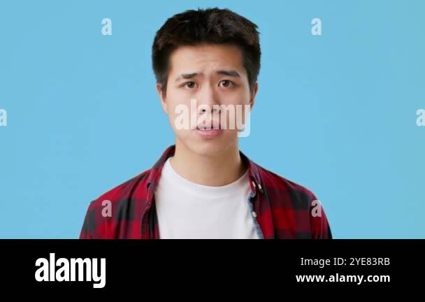 Asian young man with a shocked look raises his finger in a gesture of ...