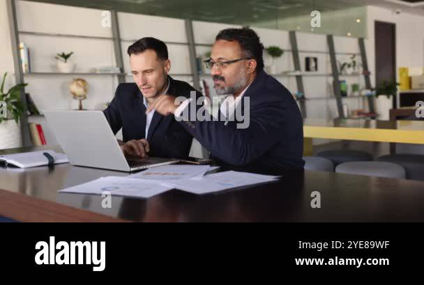 Two multiethnic business professionals collaboratively analyze data on ...