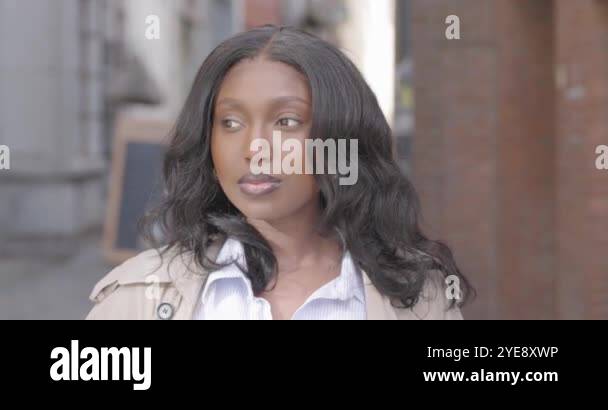 A stylish woman with long hair confidently poses in a bustling city ...