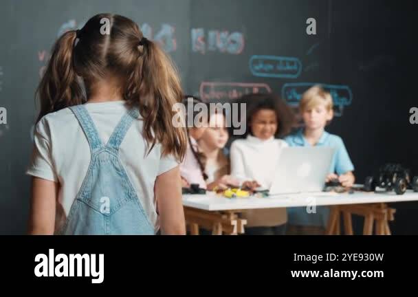 Girl smile and wave to camera while friend working or learning ...