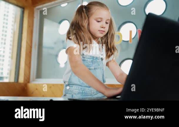 Cute girl using laptop programing software while looking at camera with ...