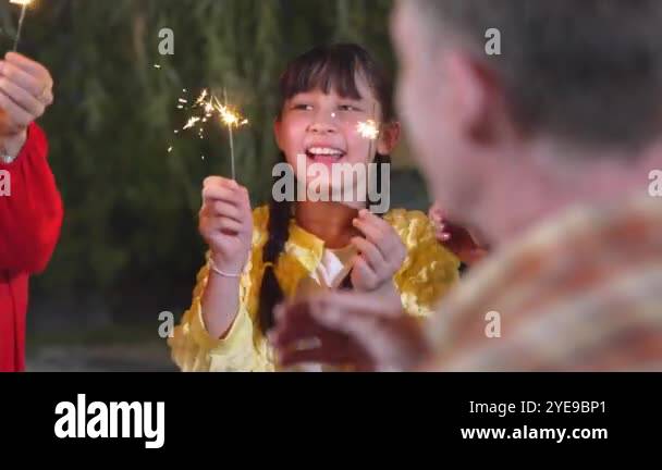 Old senior couple and girl hold sparkler in holiday celebration party. Adorable family enjoy ...