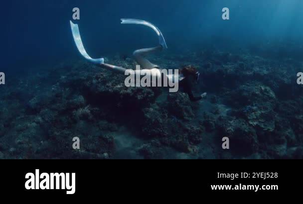 Woman freediver dives in tropical sea over corals with underwater sun ...