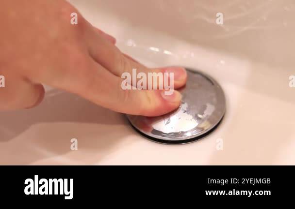 Hand pressing the bottom drain valve in the sink. Bottom valve in the ...