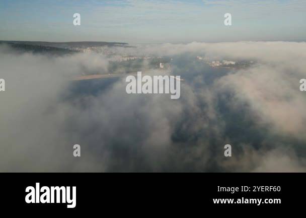 Aerial view of fog covering a coastal cityscape, revealing buildings ...