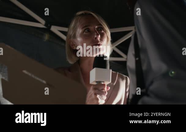 Chest up of Caucasian female crime reporter with microphone ...