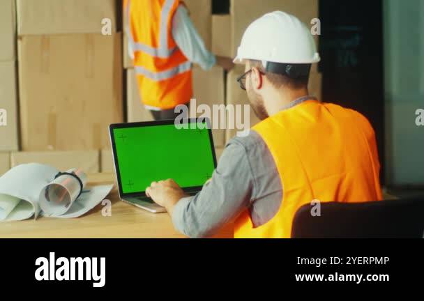 An Engineer Uses a Laptop with Green Screen for Project Monitoring and ...