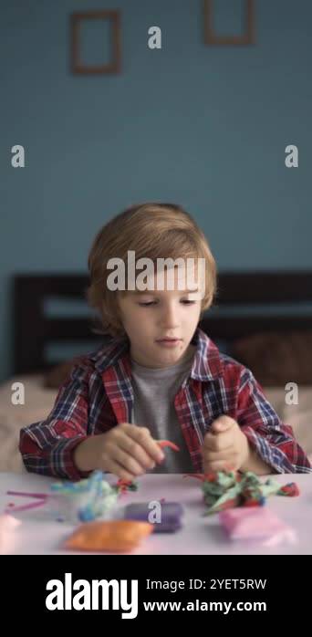 Little boy playing with colorful modeling clay at a home table, using ...