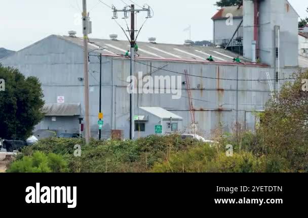 A large industrial warehouse with rusted metal siding and power lines ...
