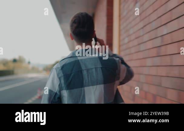 In an authentic scene of urban communication, a guy walking talks on ...