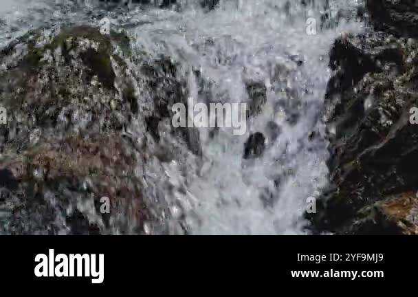 Close up fresh water flowing through the rocks over the cascade in the ...