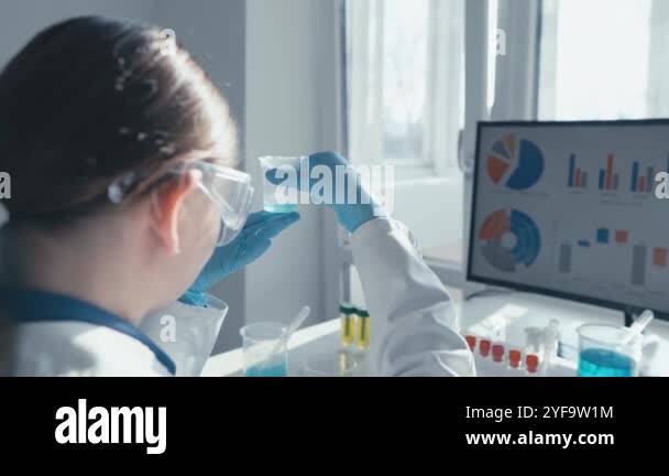 A researcher in protective gear analyzes a biological sample and ...