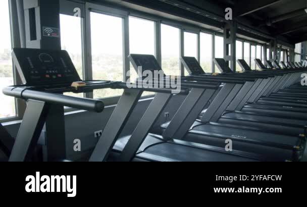 Row of high-tech treadmills in a modern gym with a scenic view through ...