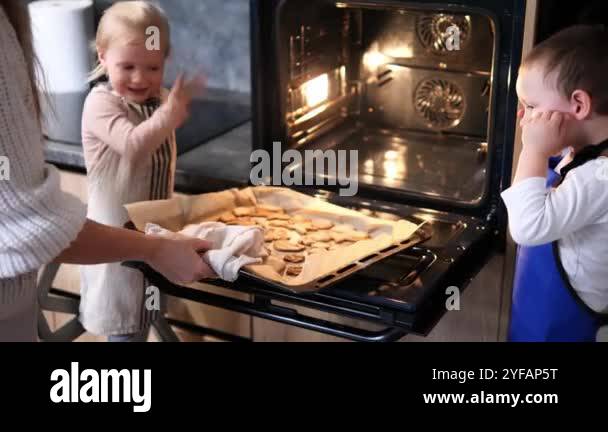 Family members baking cookies together, removing them from the oven in ...