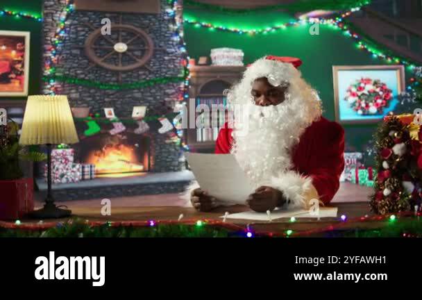 Santa Claus checking a letter while sitting in his rustic festive cabin ...