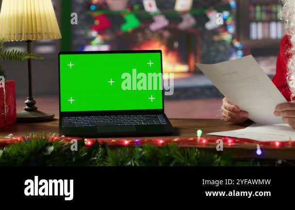 Santa Claus sitting next to copy space screen on device and reading ...